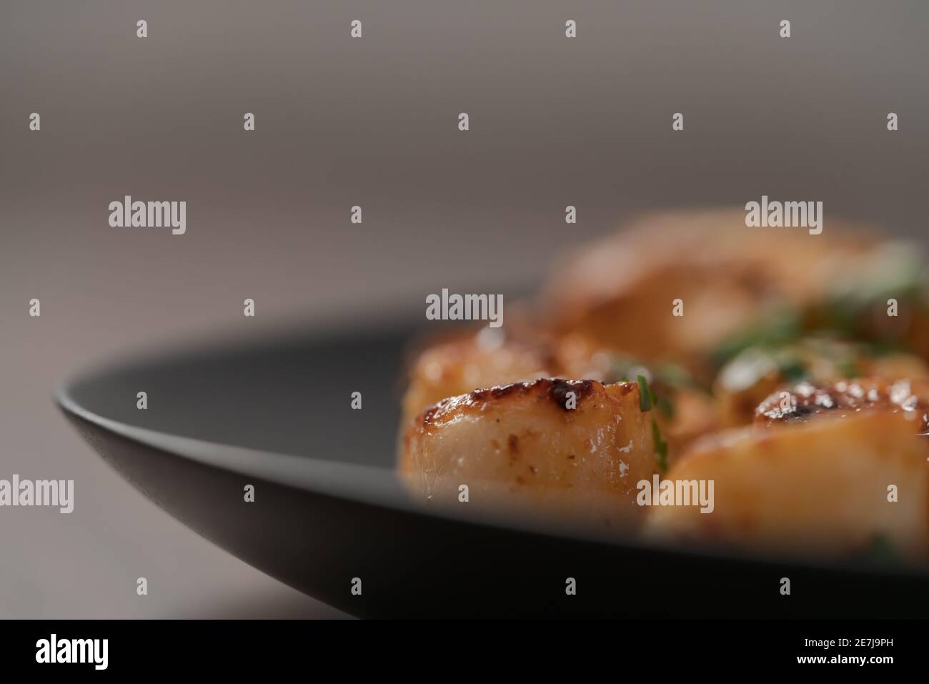 Seared scallops on black plate closeup, shallow focus Stock Photo - Alamy