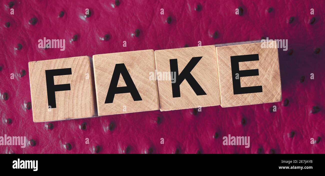 FAKE word written in wooden blocks on red leather. Fake or real news ...