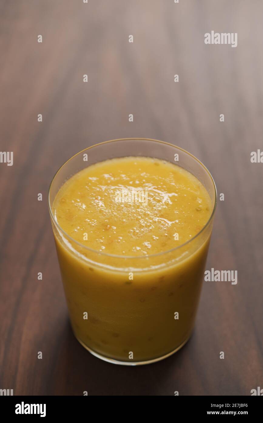 Mango lulo smoothie on walnut wood table with copy space, shallow focus ...