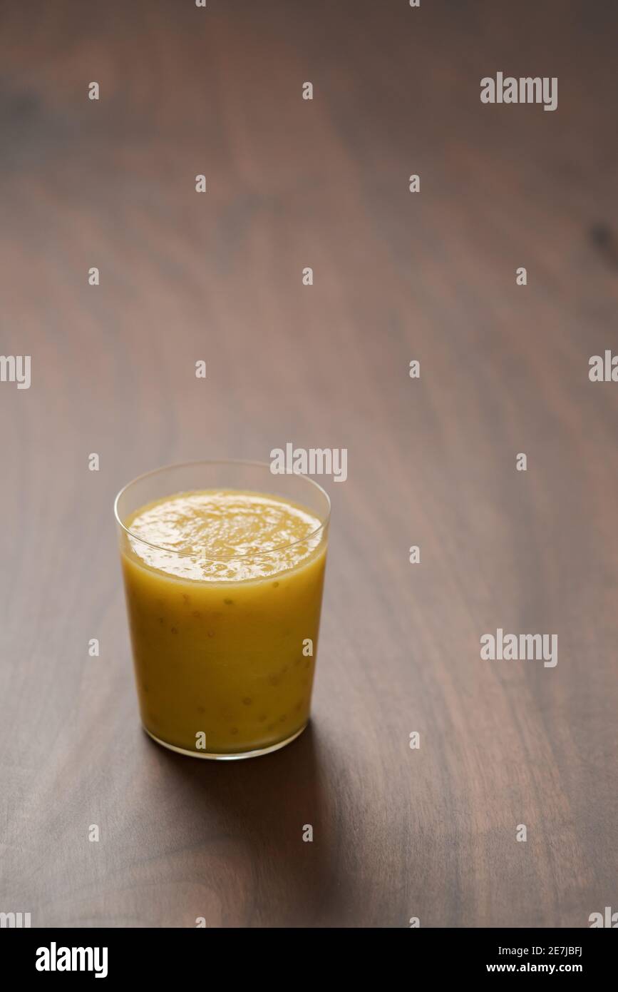 Mango lulo smoothie on walnut wood table with copy space, shallow focus ...