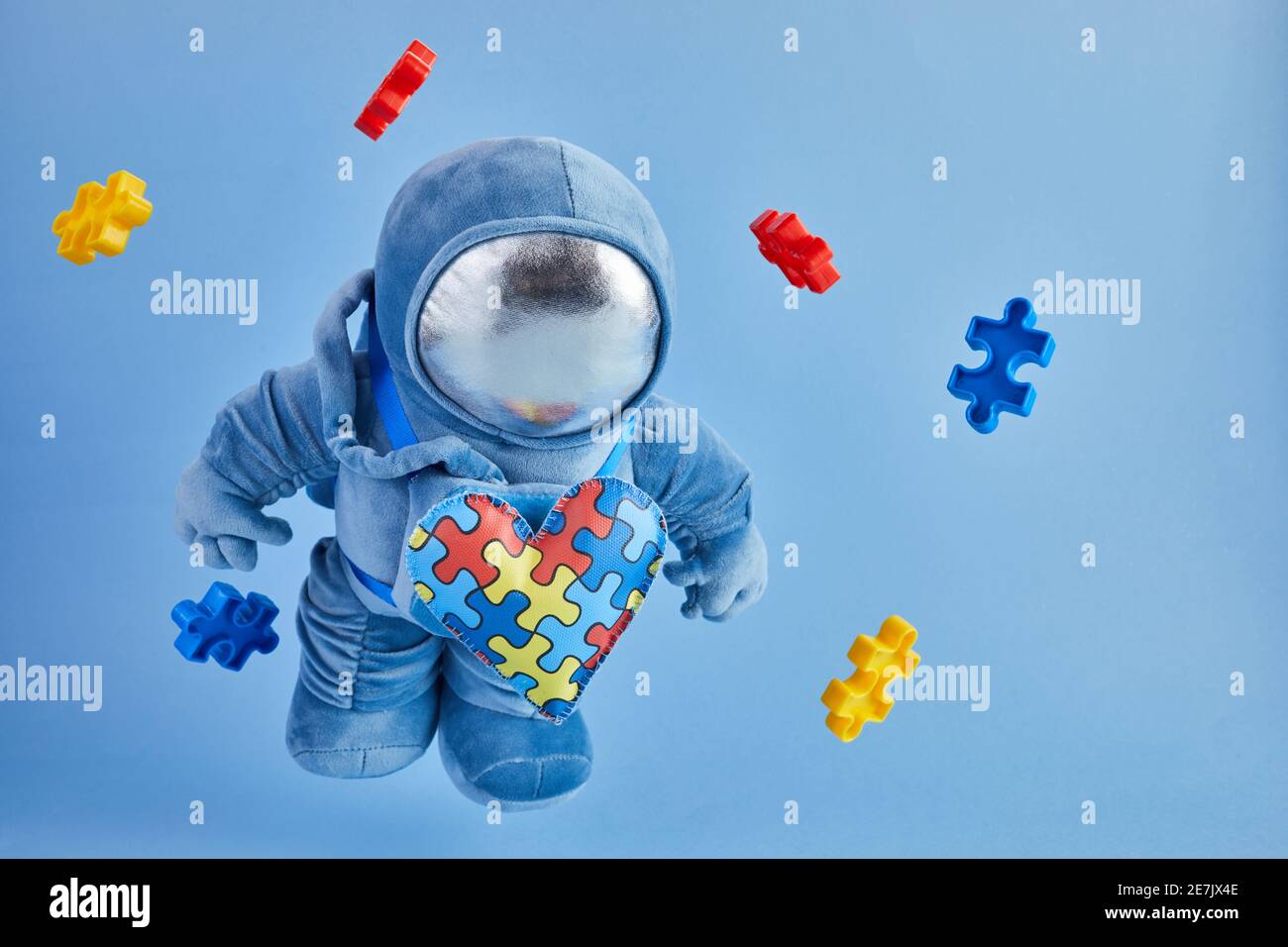 Autism awareness background. Blue plush astronaut toy with puzzle heart ...