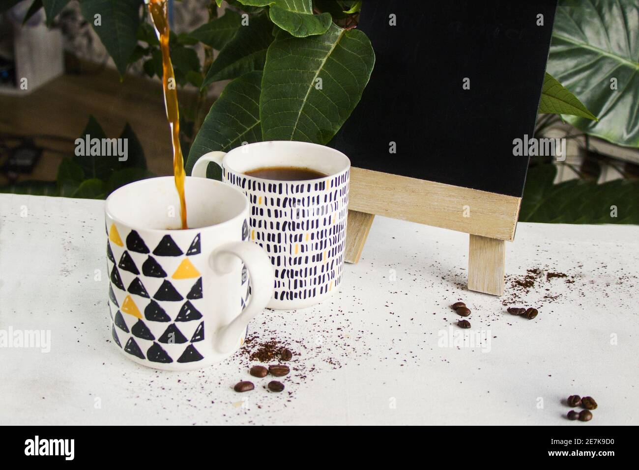 Pouring tea in a cup with a blank wooden blackboard in the background ...