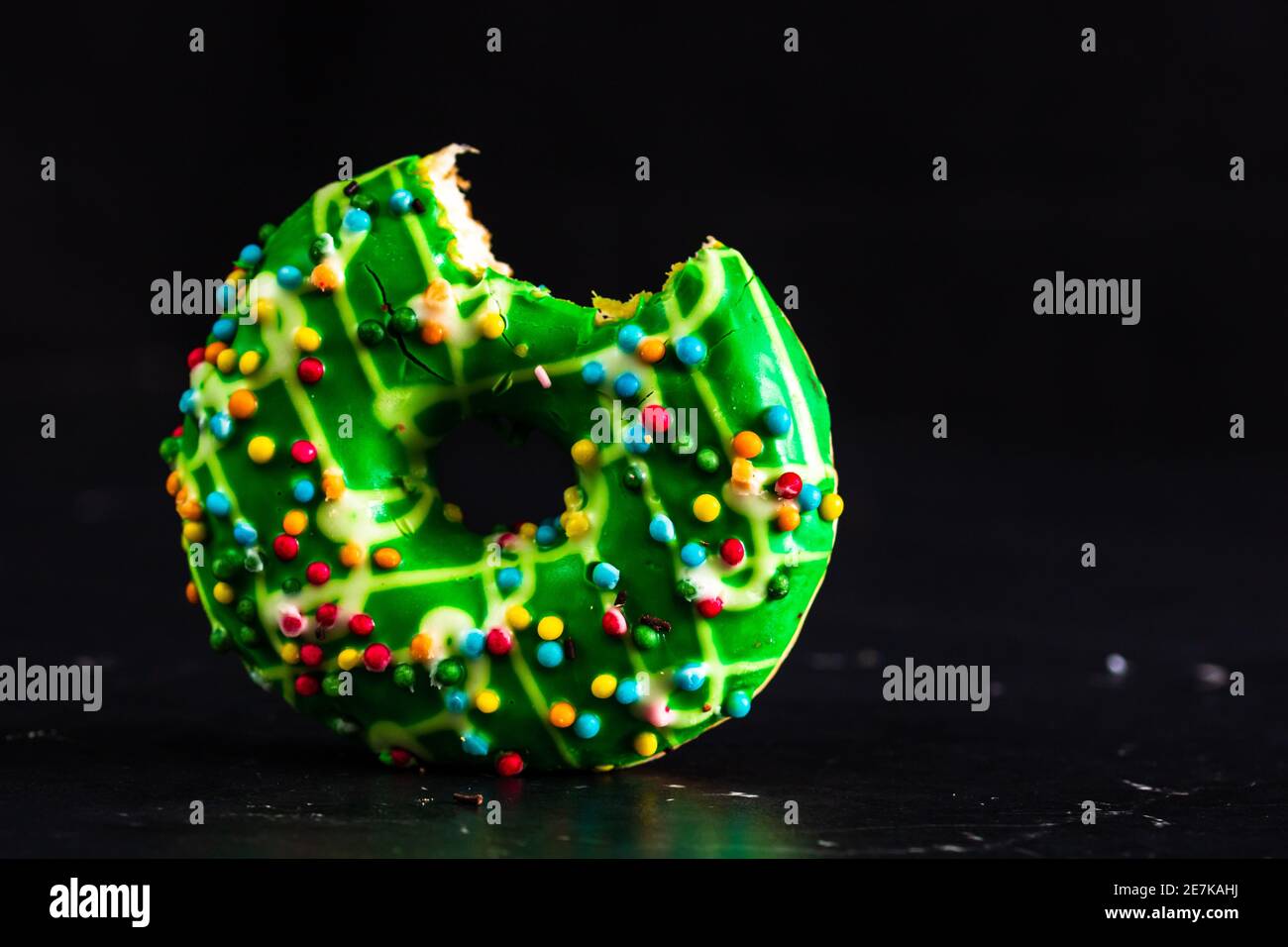 Green glazed donut with sprinkles isolated. Close up of colorful bitten donut Stock Photo - Alamy