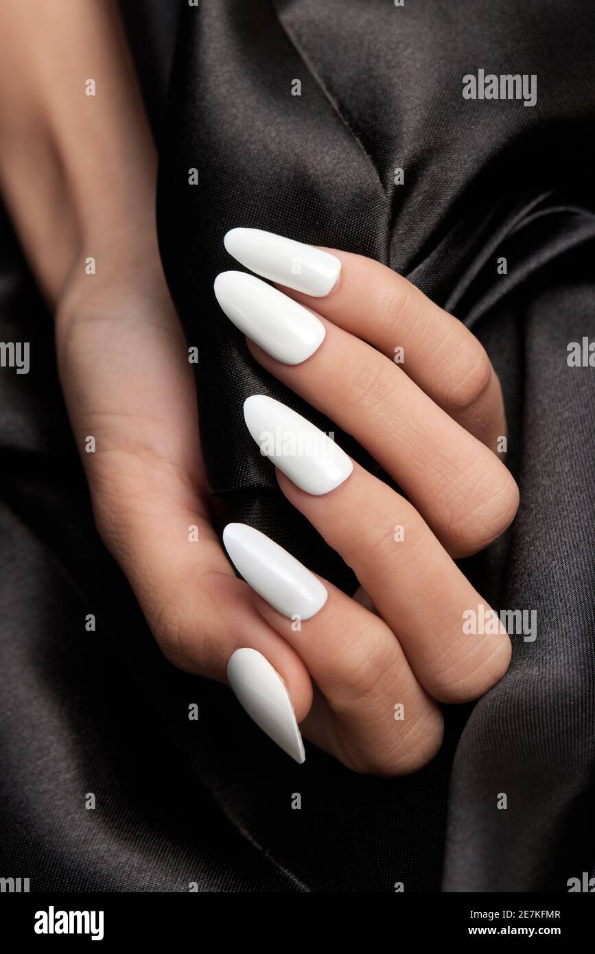 Female hand with long white nails holding a black satin fabric Stock ...