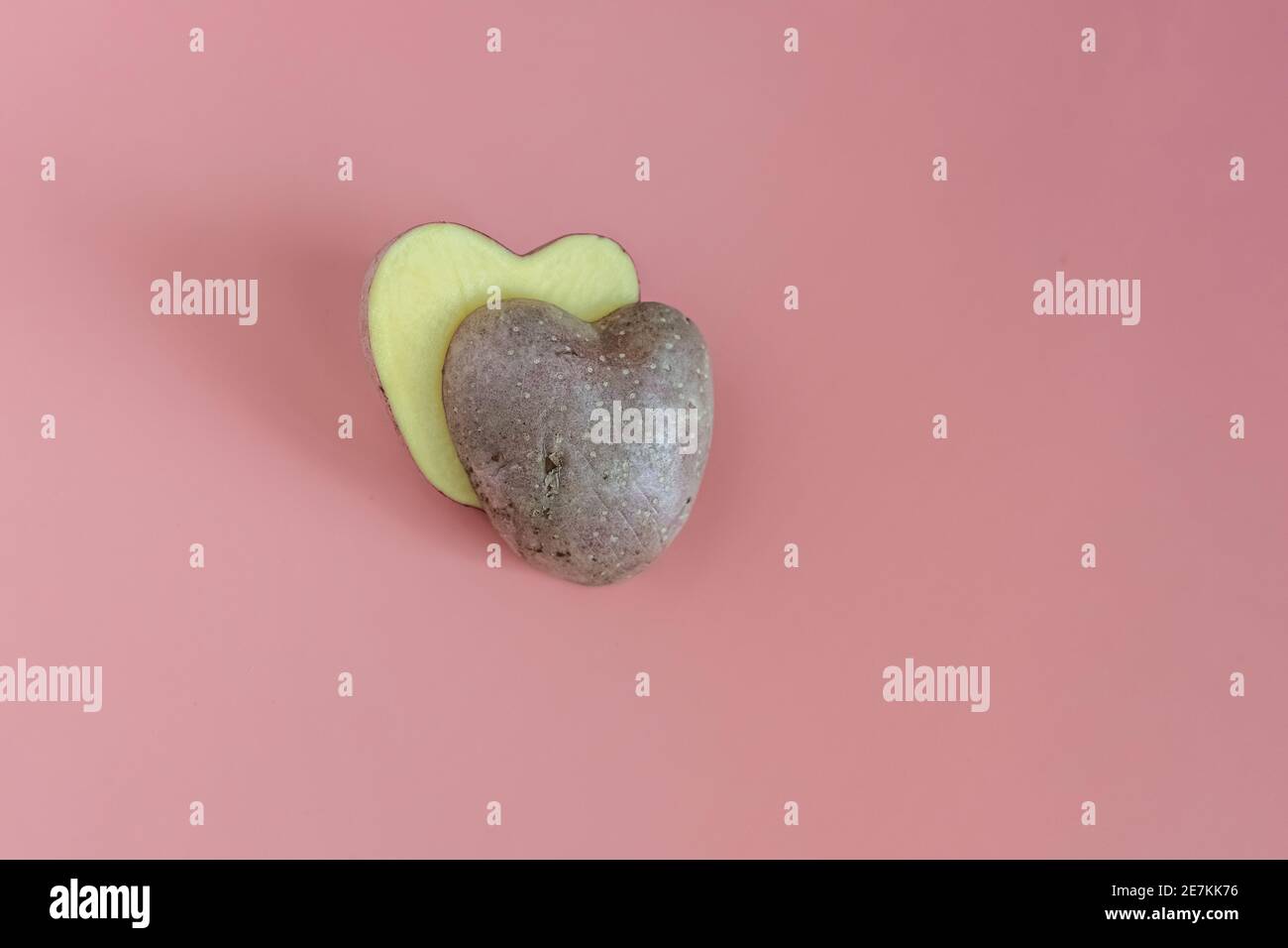 Heart shaped potatoes cut in half on a pink background. Concept of ...