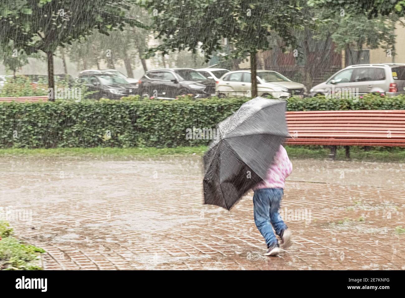 A little girl is having fun running around with an umbrella in the ...