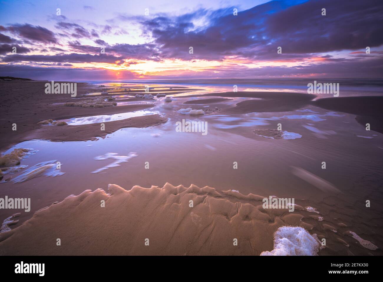 Maritime landscape at sunset with reflection of clouds in low tide ...