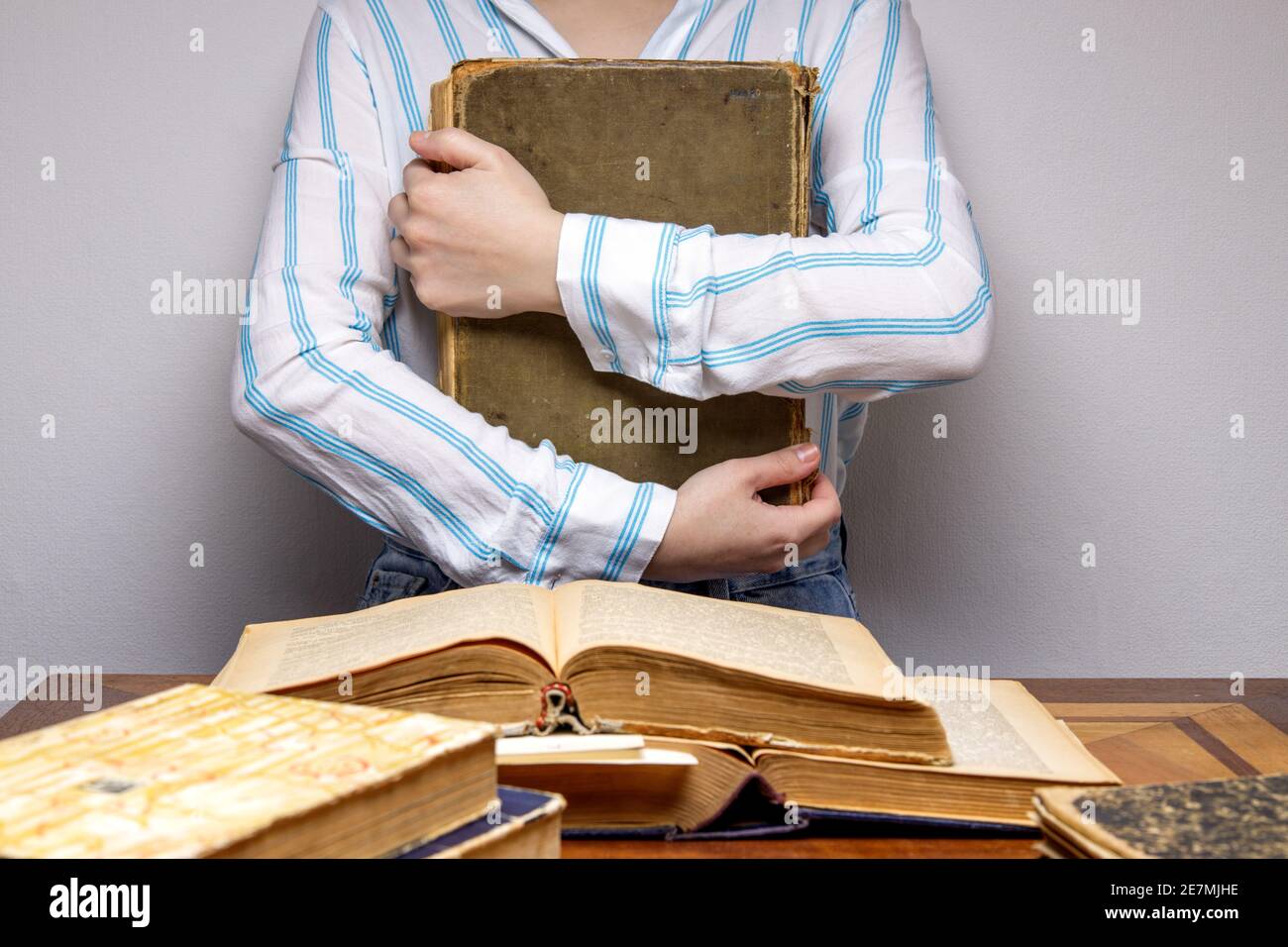hand of an invisible person holds hugs an old book Stock Photo - Alamy
