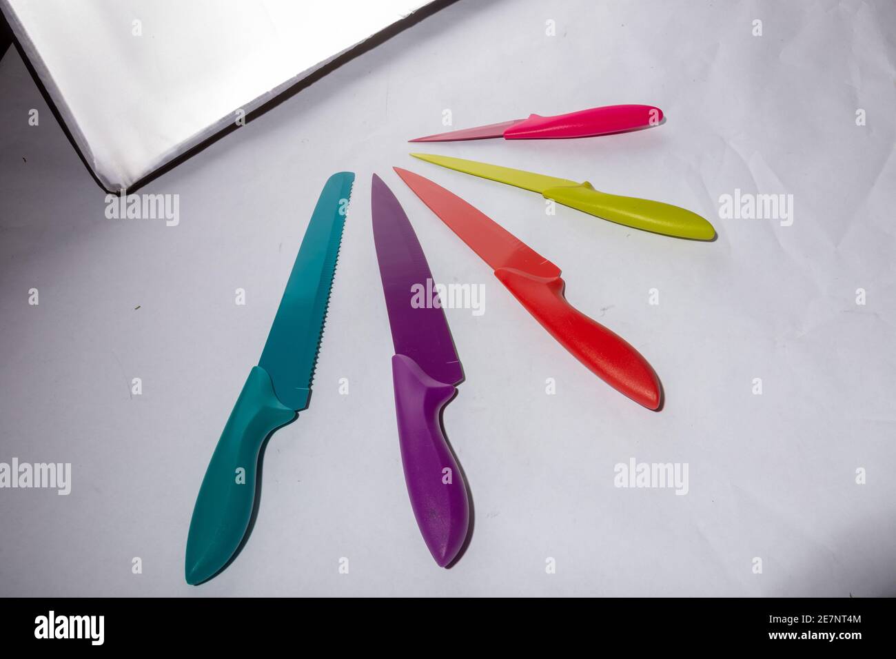 High angle shot of colorful sharp knives on a white surface under the ...