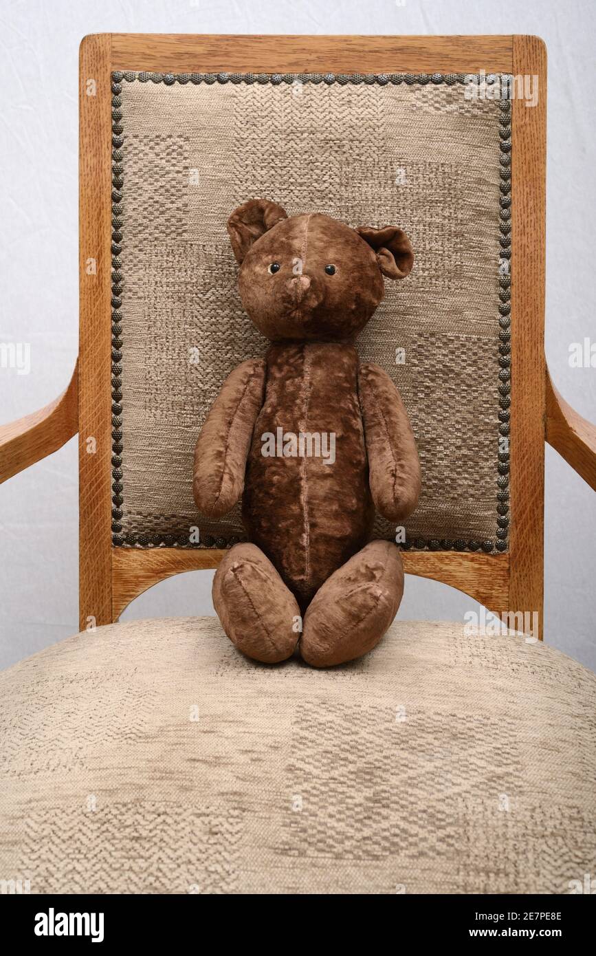 shabby teddy bear sitting in an old vintage armchair, deadpan ...