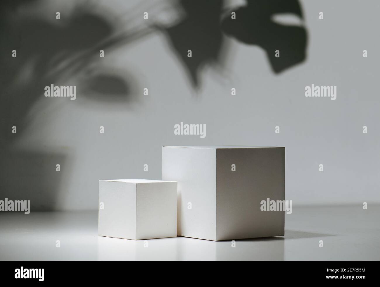 Composition of two white cubes over white wall with a shadow of big ...