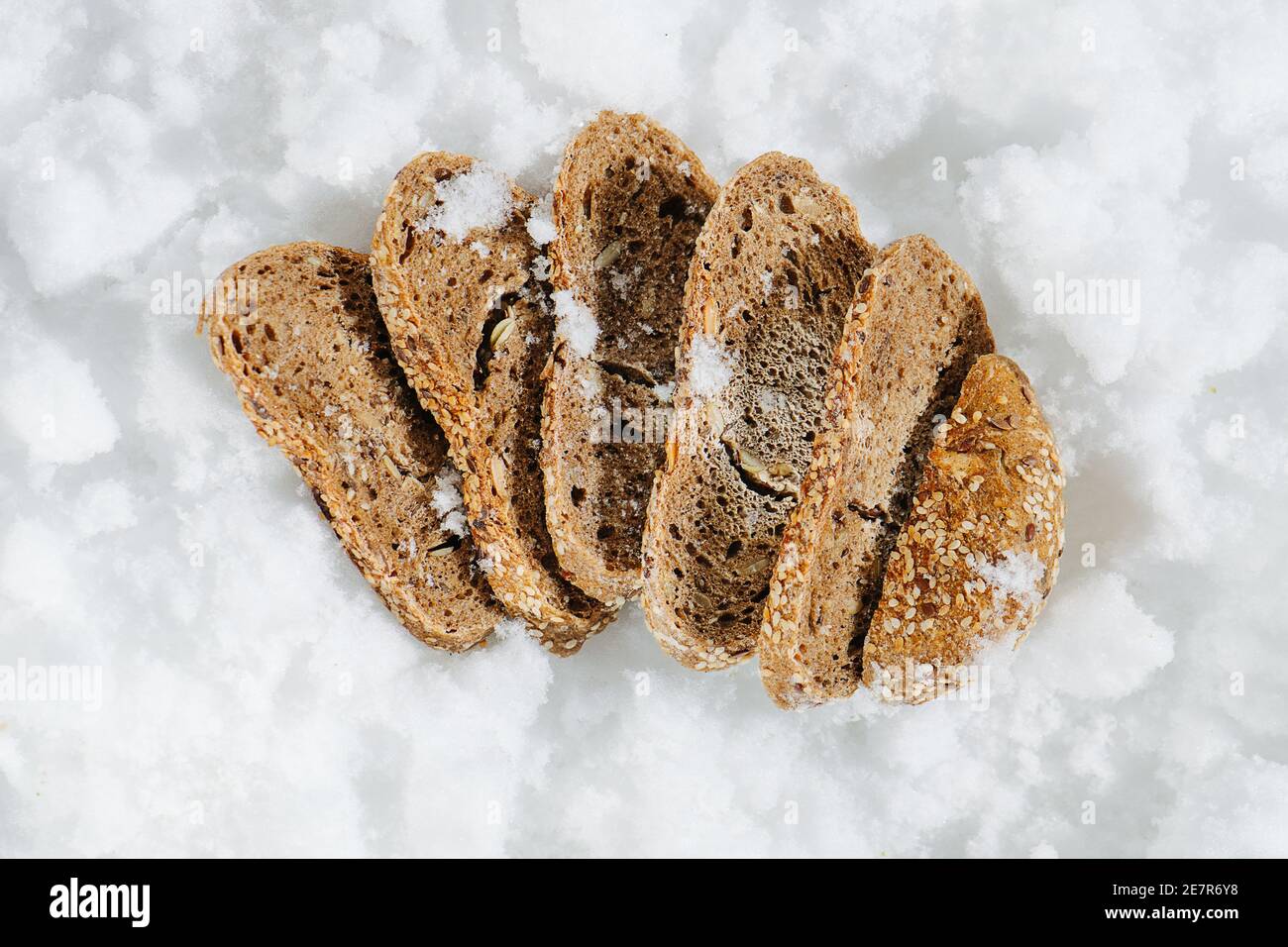 Nicely arranged frozen grey bread slices in a grinded ice. top view ...
