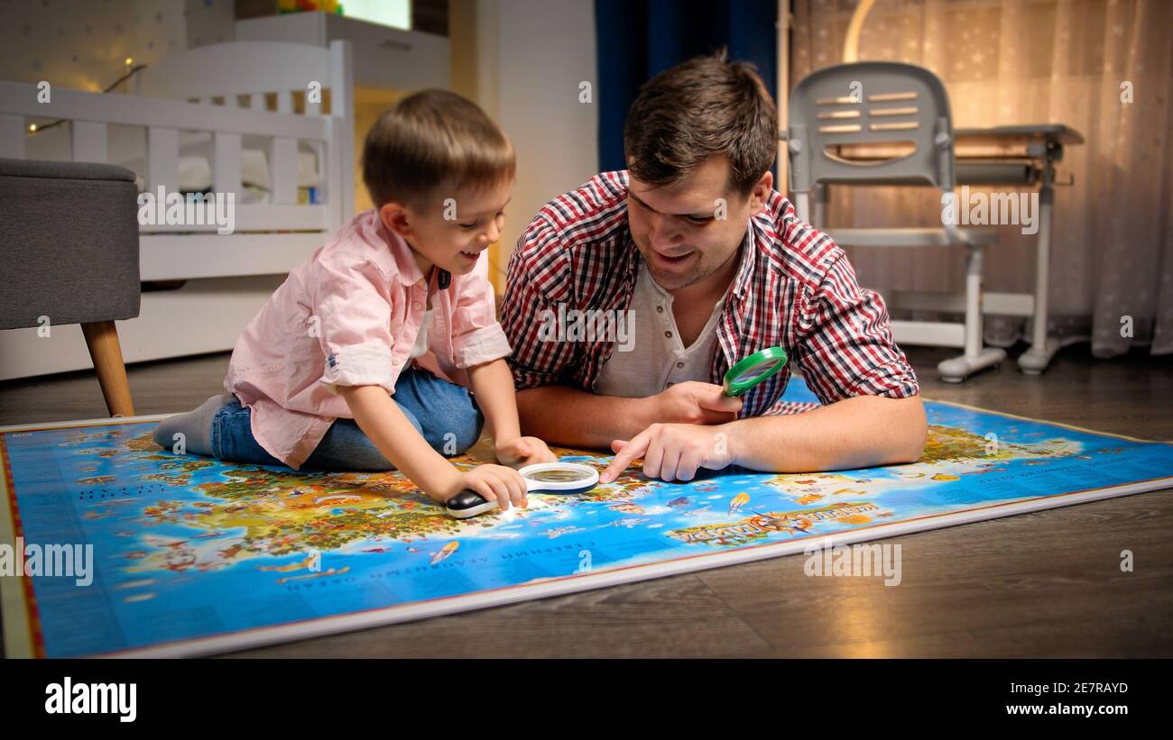 Happy smiling little boy with young father exploring world map and ...