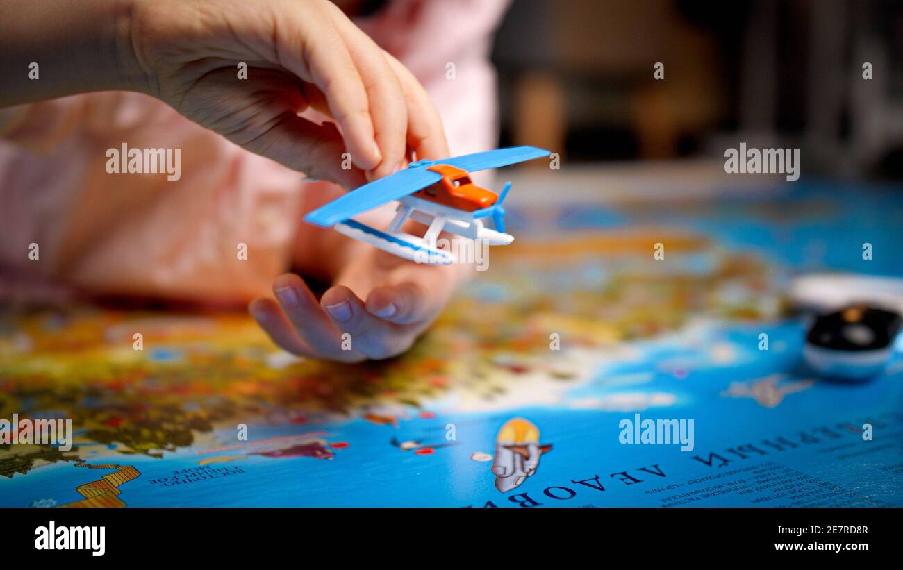 Closeup of little boy playing with small toy airplane on big world map ...