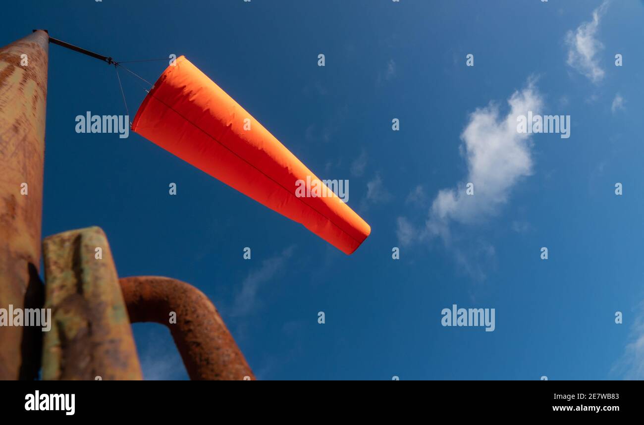a large red orange inflated wind sock viewed up iron pole from beneath ...