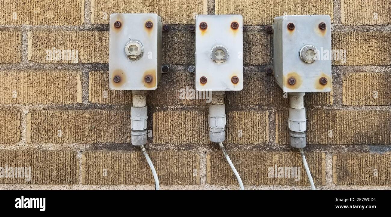 Three old utility boxes on an old brick wall Stock Photo - Alamy