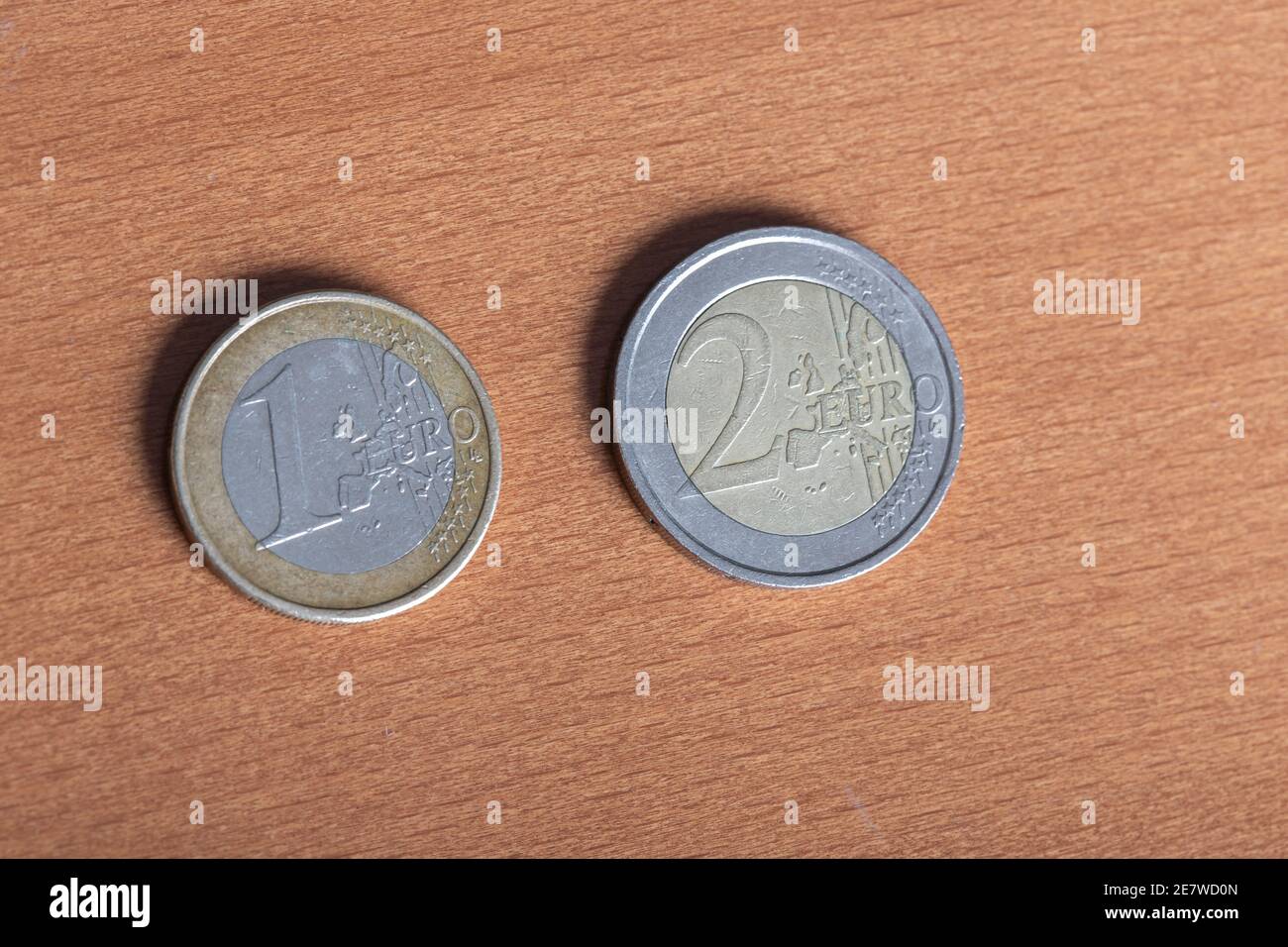 Top view shot of two gold and silver euro coins on a wooden table ...
