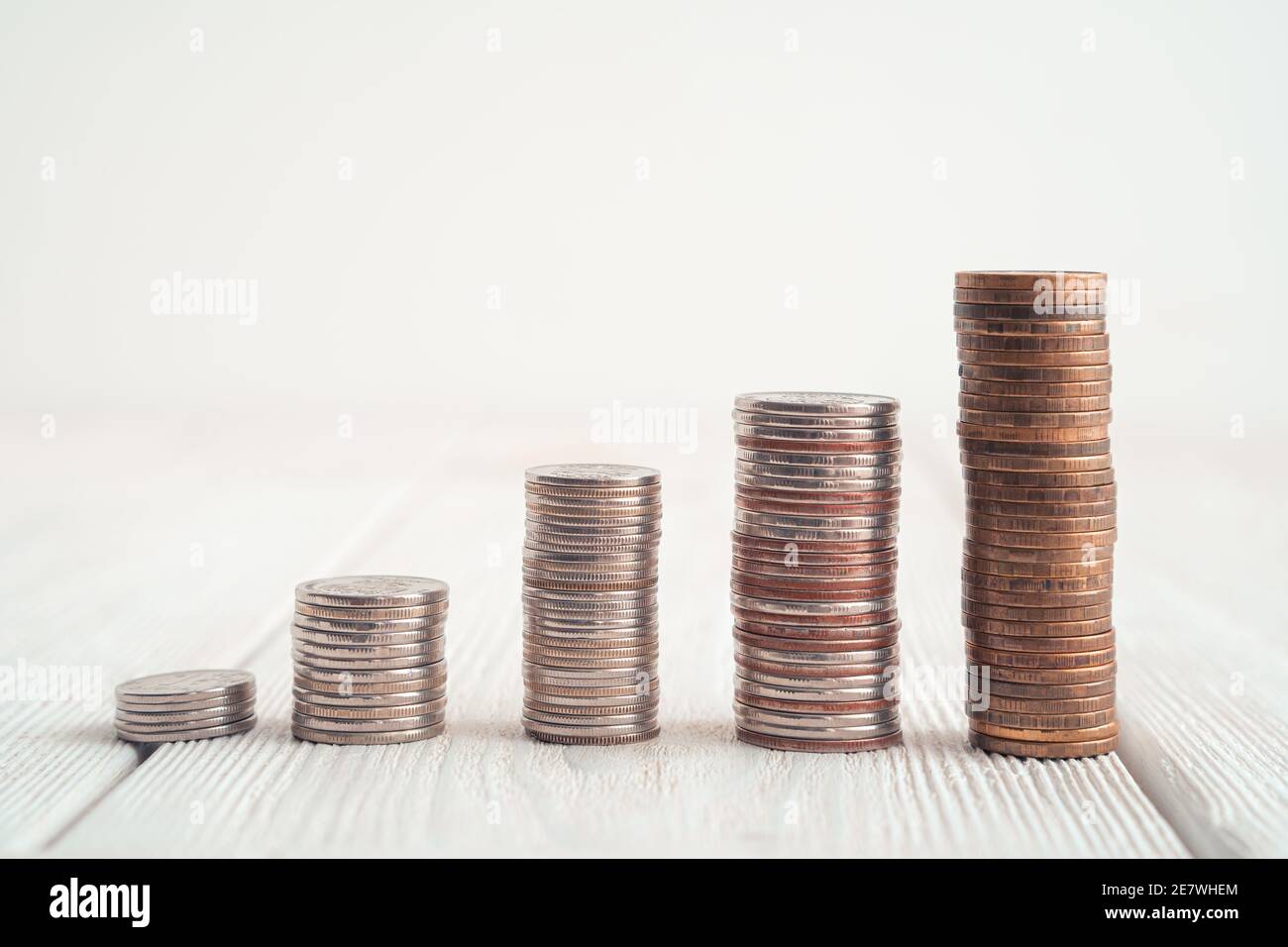 Stacks of coins are arranged by height on a light background. Side view ...