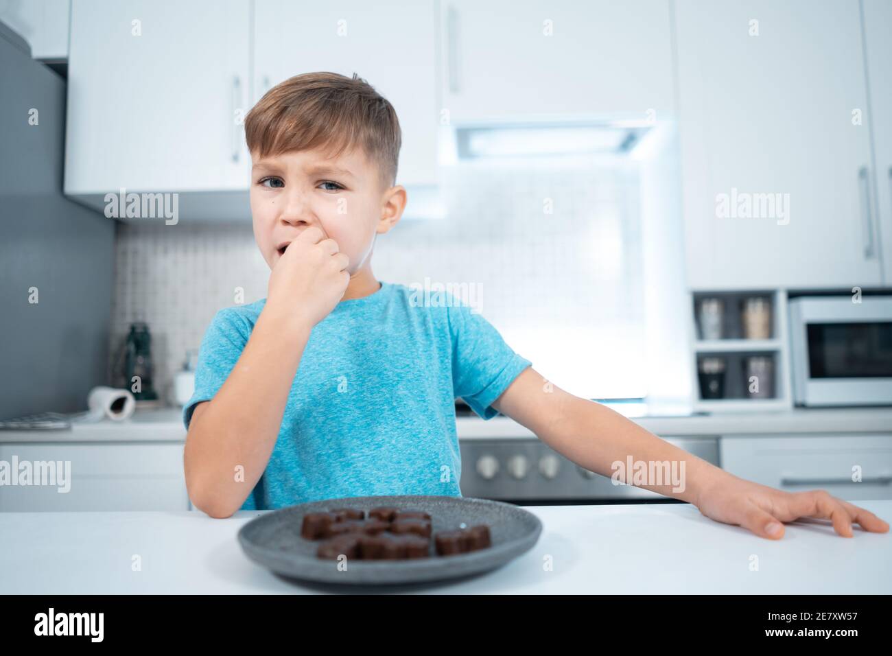 kid boy eating or biting chocolate sweets or candies at modern home ...