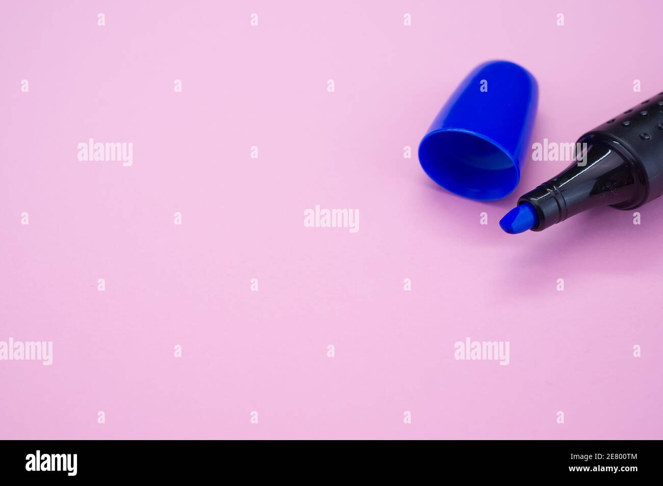 Closeup of a broad blue marker with a cap isolated on a pink background ...
