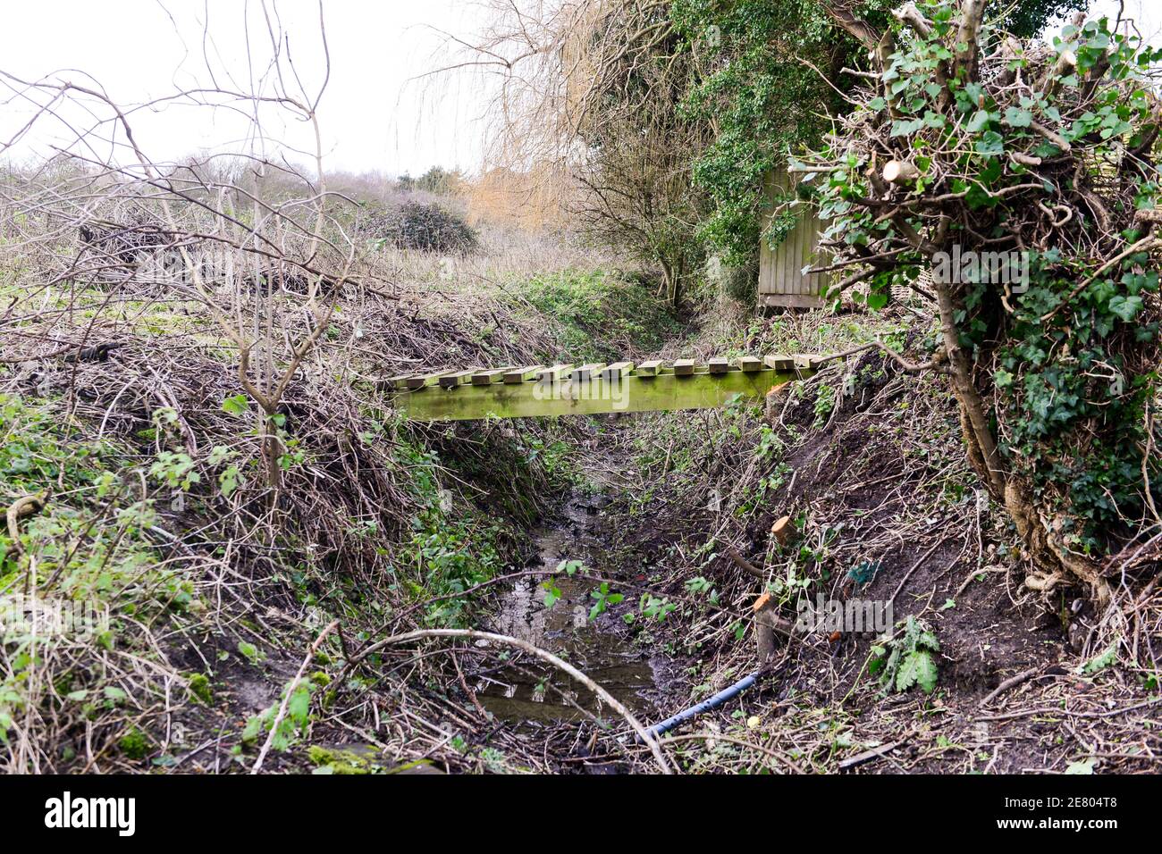small wooden footbridge with no railings spanning small waterway in ...