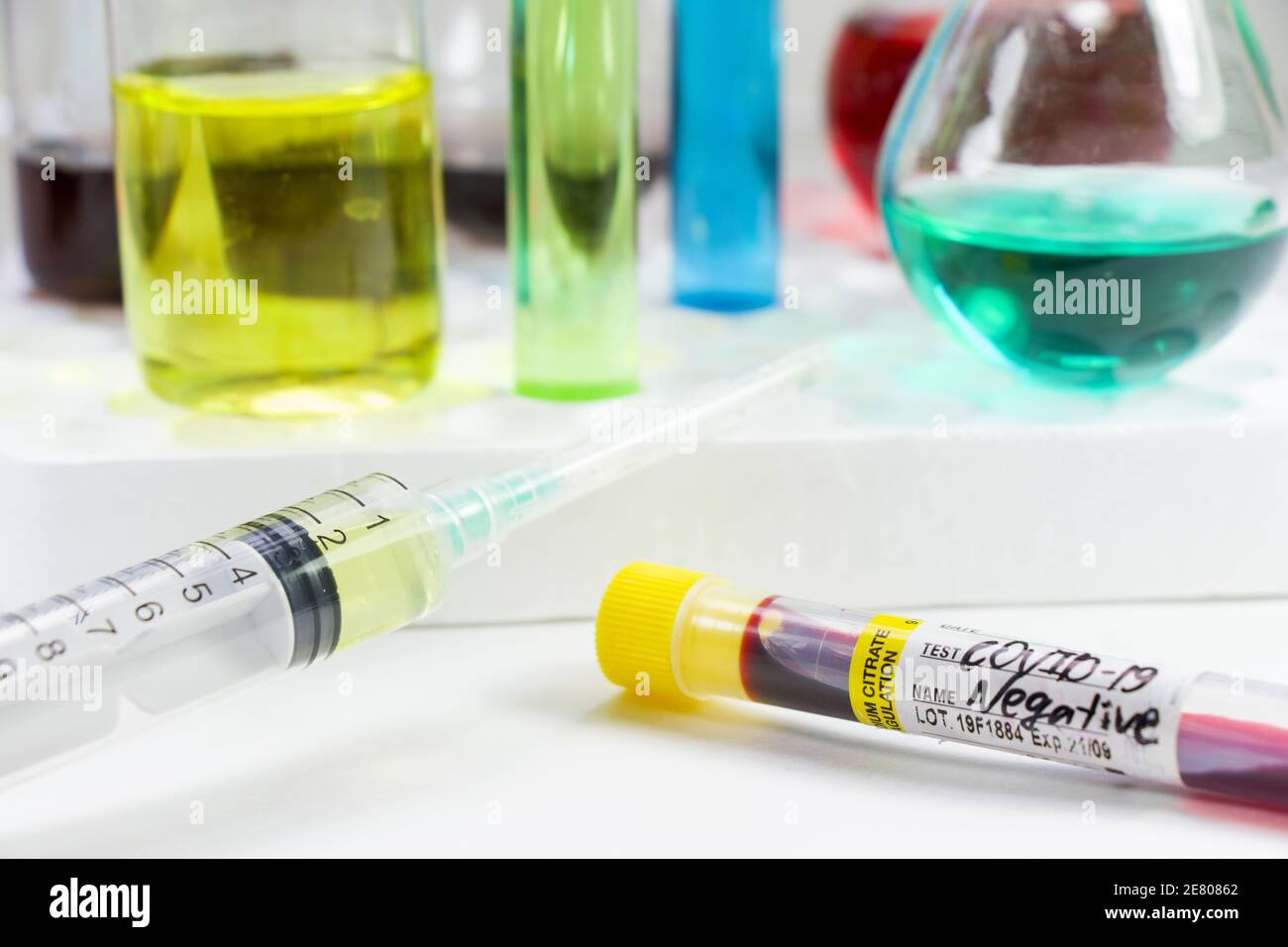 Closeup shot of a blood sample test and a syringe on glass flasks ...