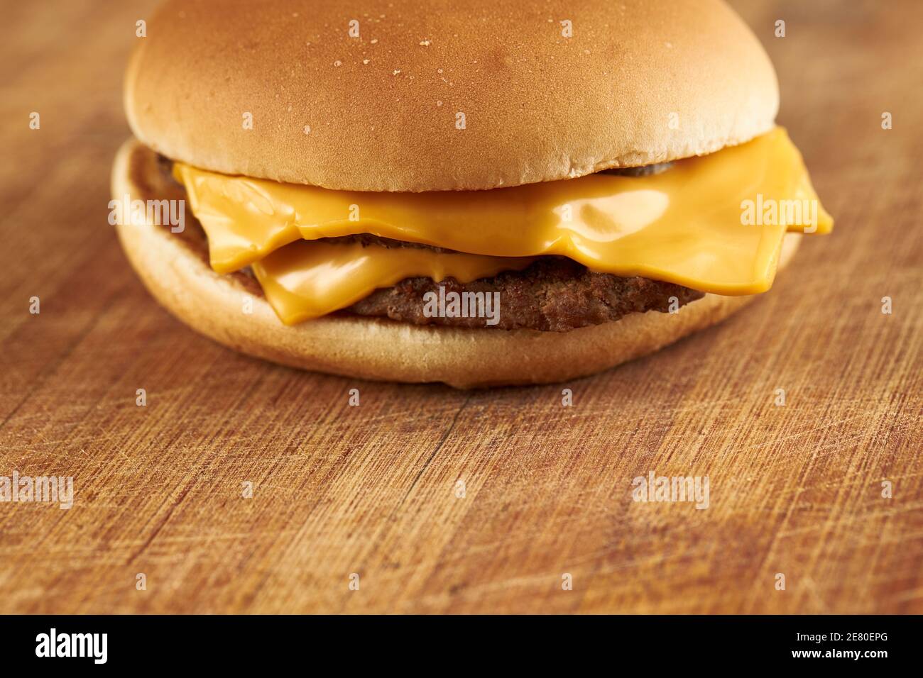thin cheeseburger or hamburger on a wooden board with diagonal lines ...