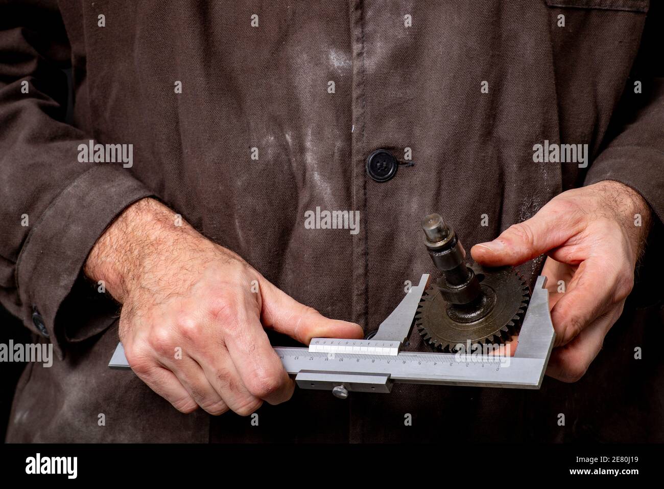 Mechanic measuring gears. Work in a mechanical workshop. Dark ...