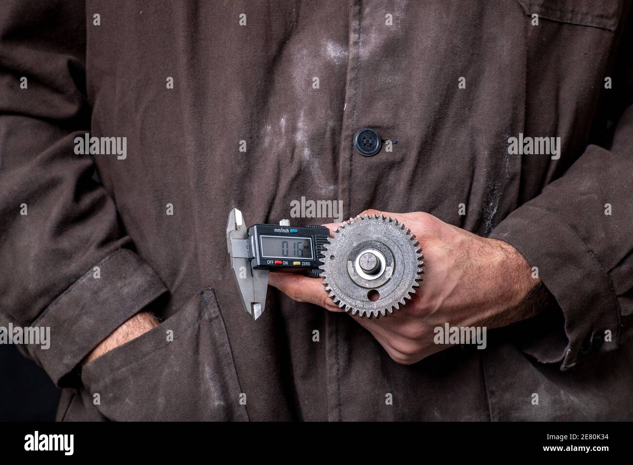 Mechanic measuring gears. Work in a mechanical workshop. Dark ...
