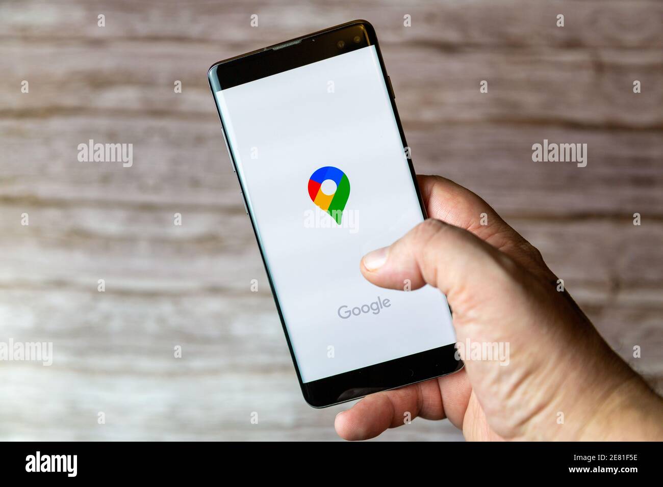 A hand holding a mobile phone or cell phone with the Google Maps app ...