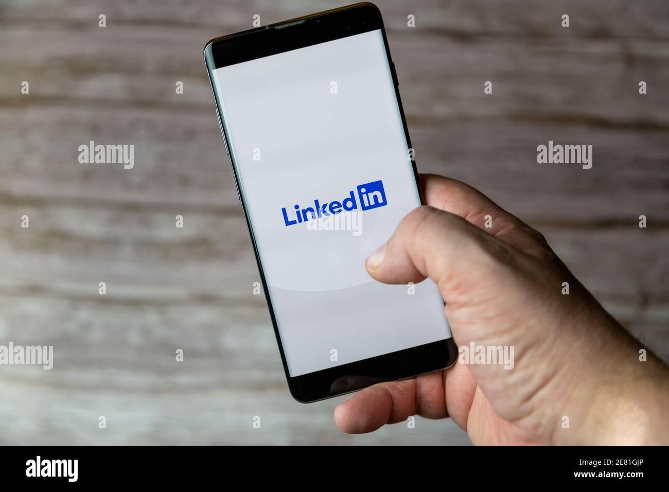 A hand holding a mobile phone or cell phone with the Linkedin app open ...
