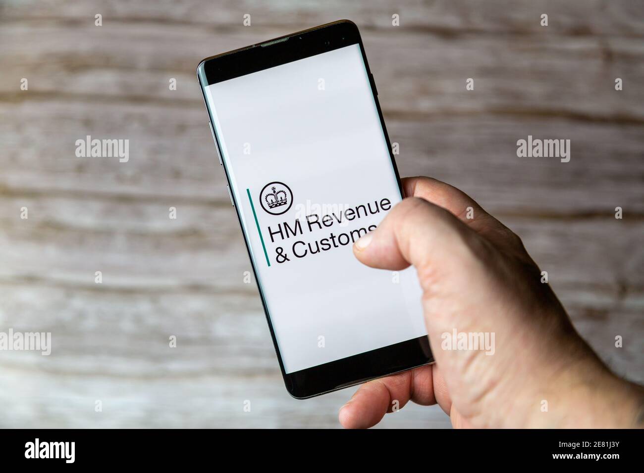 A hand holding a mobile phone or cell phone with the HM revenue and ...