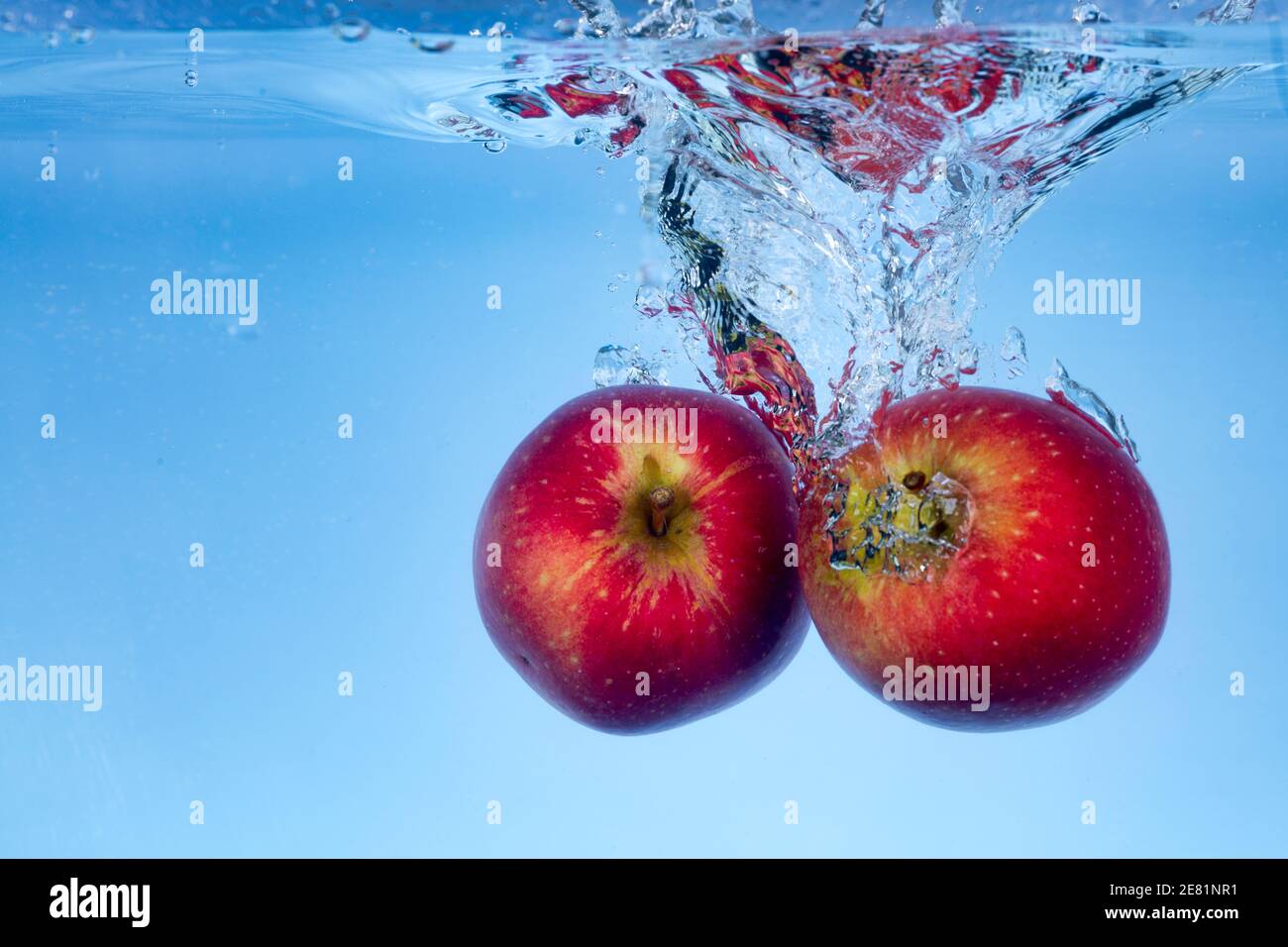 Freeze motion photo of two red apples dropped into water to be washed ...