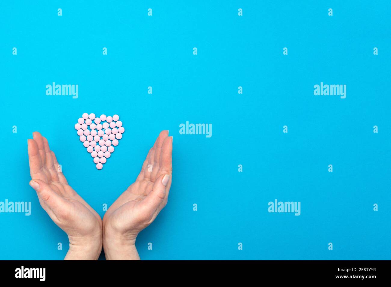 Pink pills in the shape of a heart on a blue background and female ...