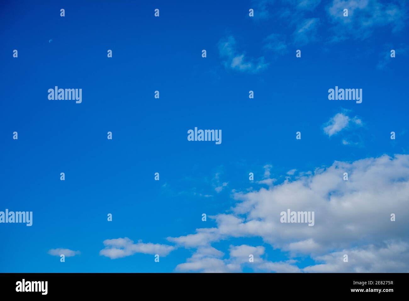 Bright tropical sky with cumulus clouds and a pale, half moon over ...