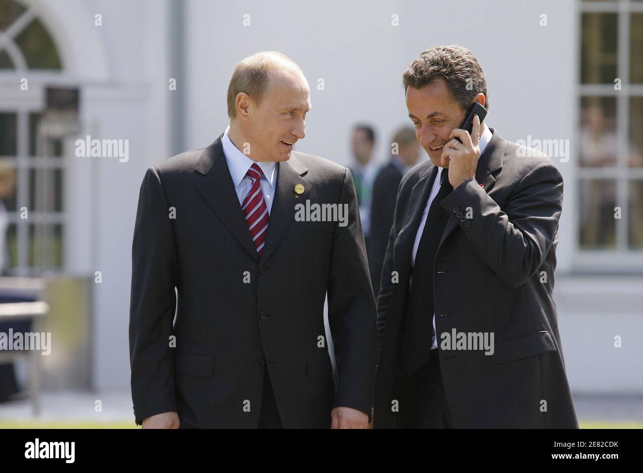 French President Nicolas Sarkozy (L) takes a phone call as he stands ...