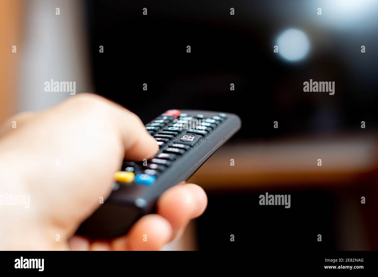 Male hand holding a TV remote and trying to turn on the TV Stock Photo ...