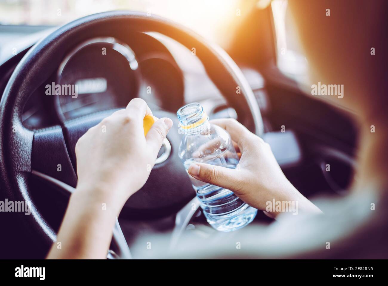 A woman driver drinking water while driving a car Stock Photo - Alamy