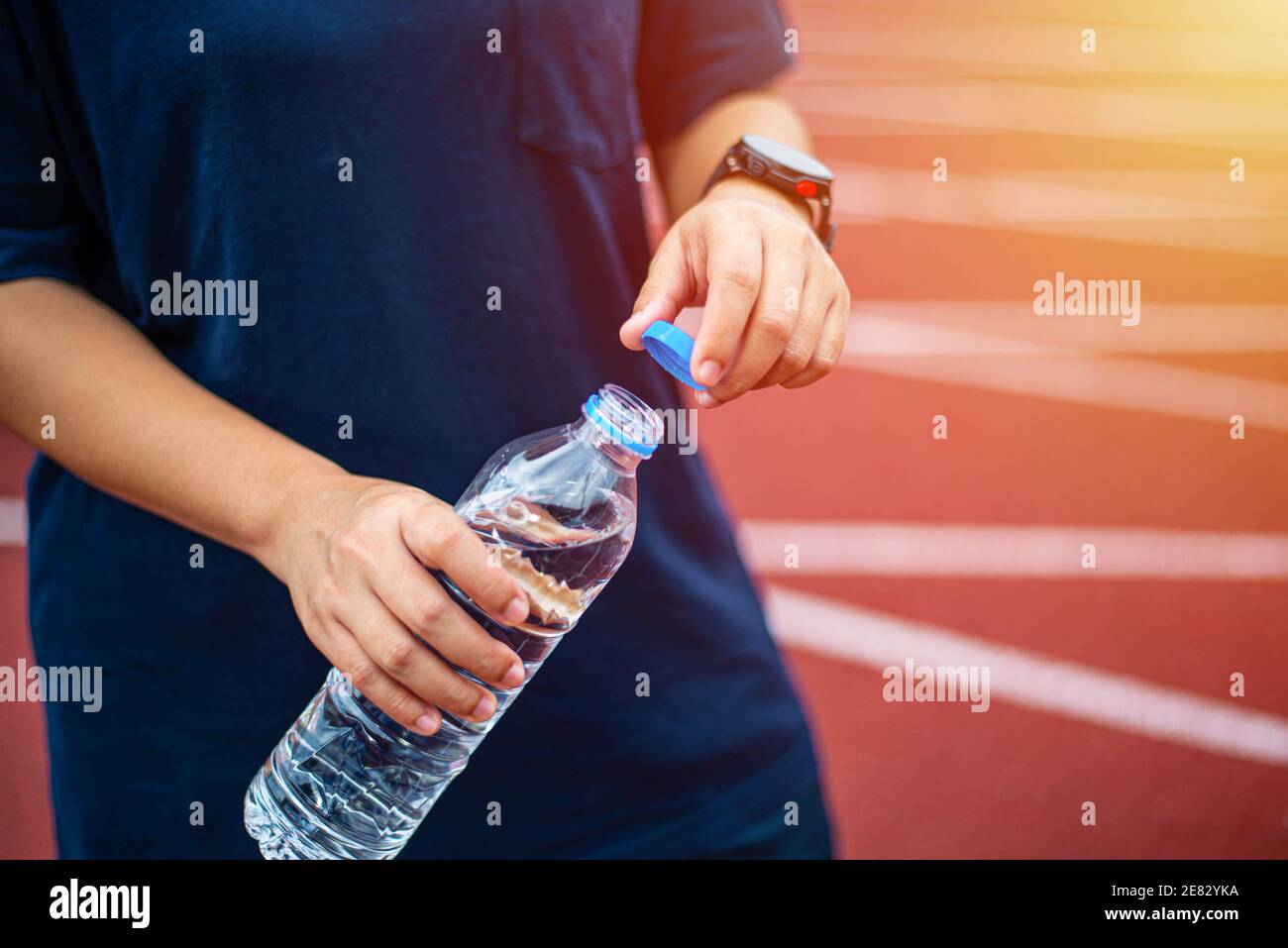 Athletes are in running track and use the hand to open the water bottle ...