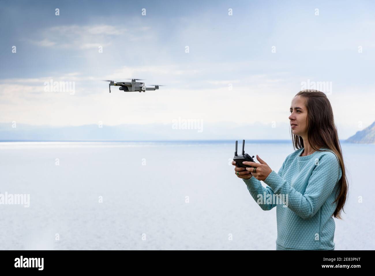 Beautiful young woman having fun with a mini drone outdoors. The girl ...