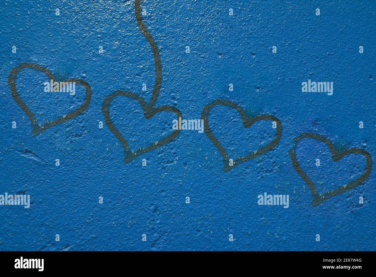 Blue painted wall with four aligned heart signs written in disorder ...