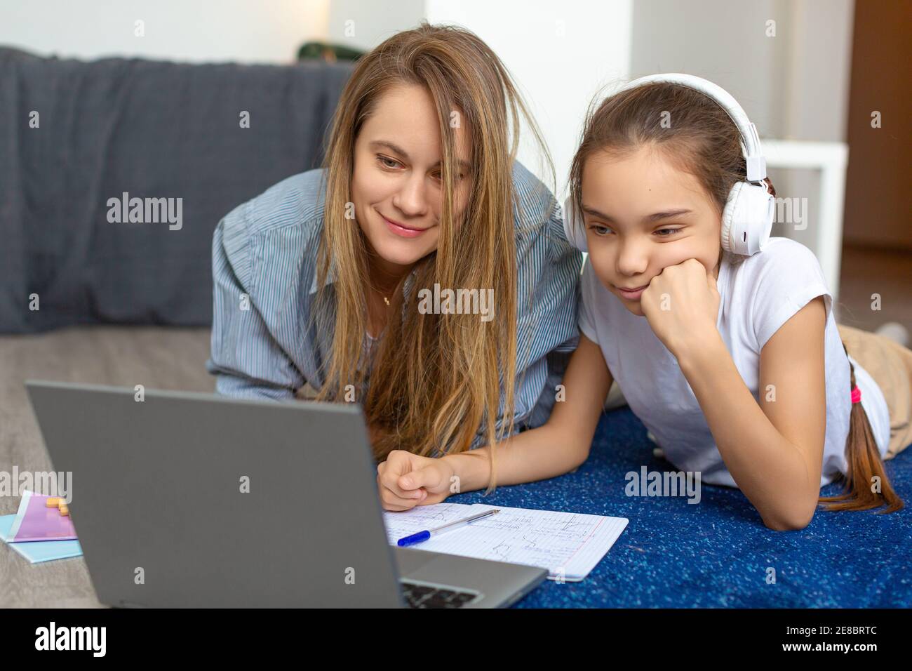 Mom and daughter are doing homework in front of a laptop monitor, lying ...