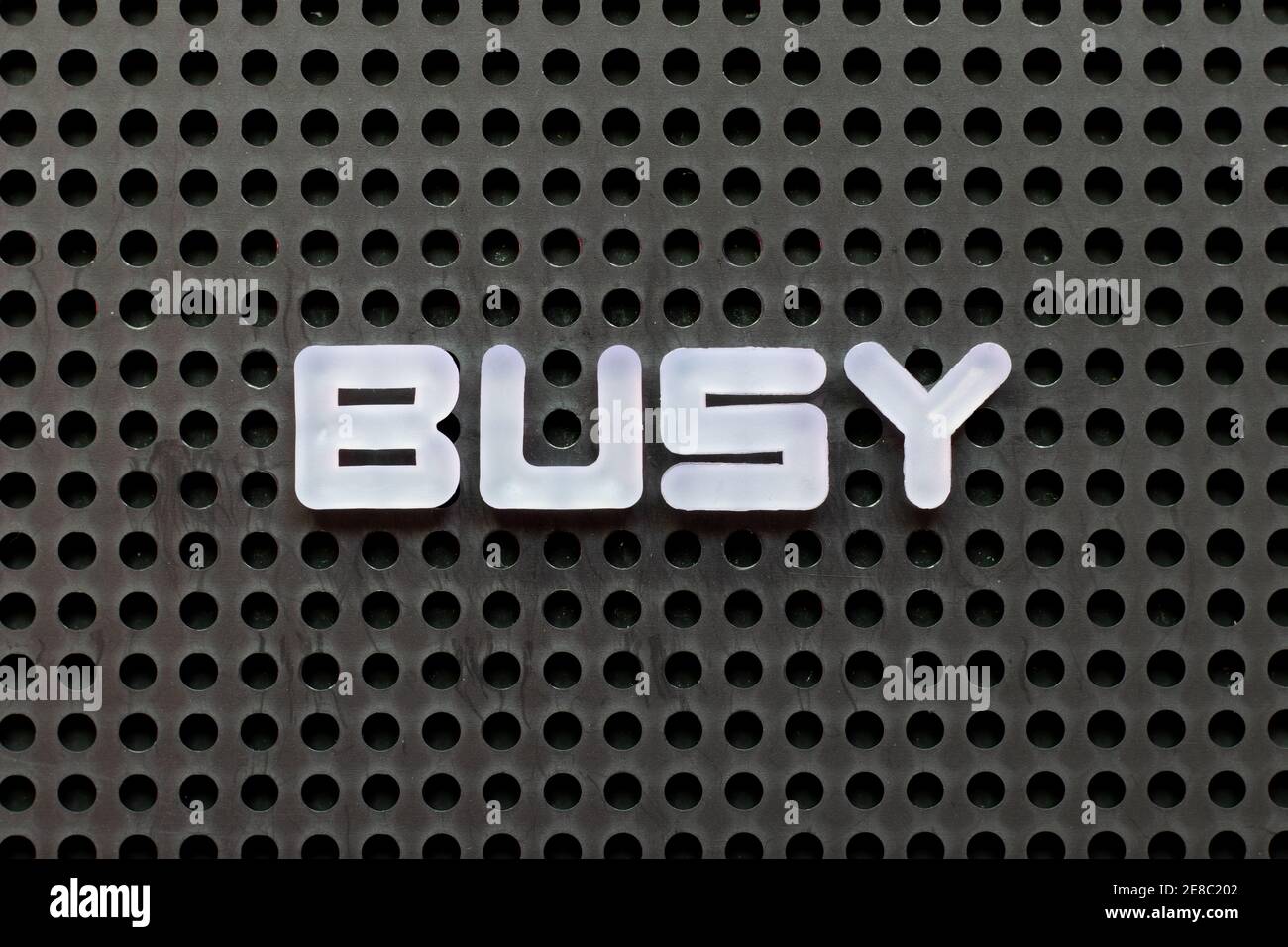 White color letter in word busy on black pegboard background Stock ...