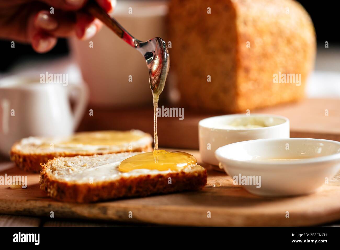 Side view on spreading bread slice with honey Stock Photo - Alamy