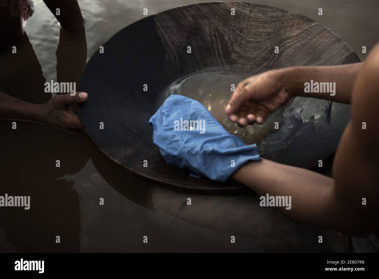 Gold miners processing gold particles with mercury amalgamation on a ...