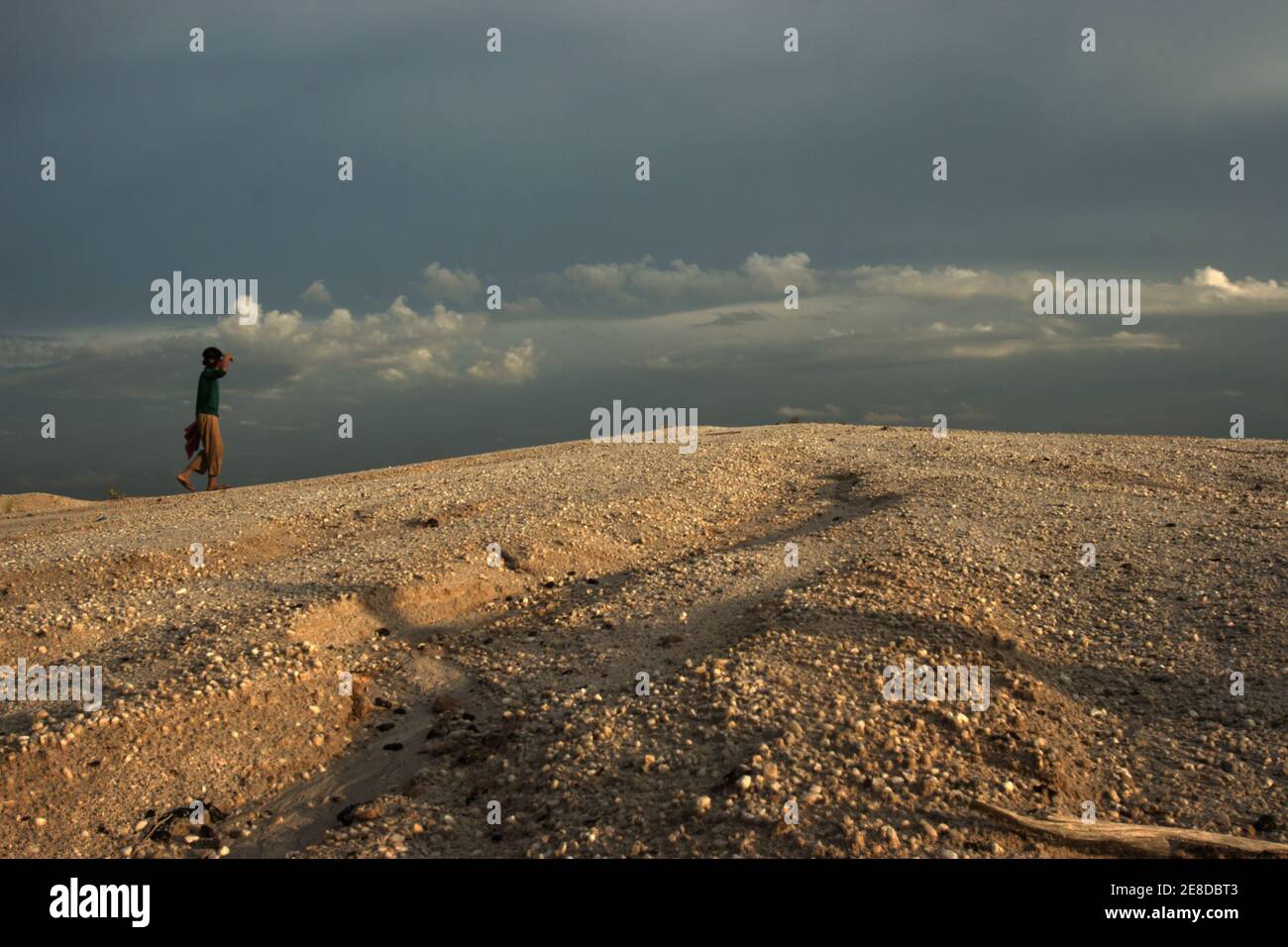 A gold miner walking on the sandy landscape of the small-scale gold ...