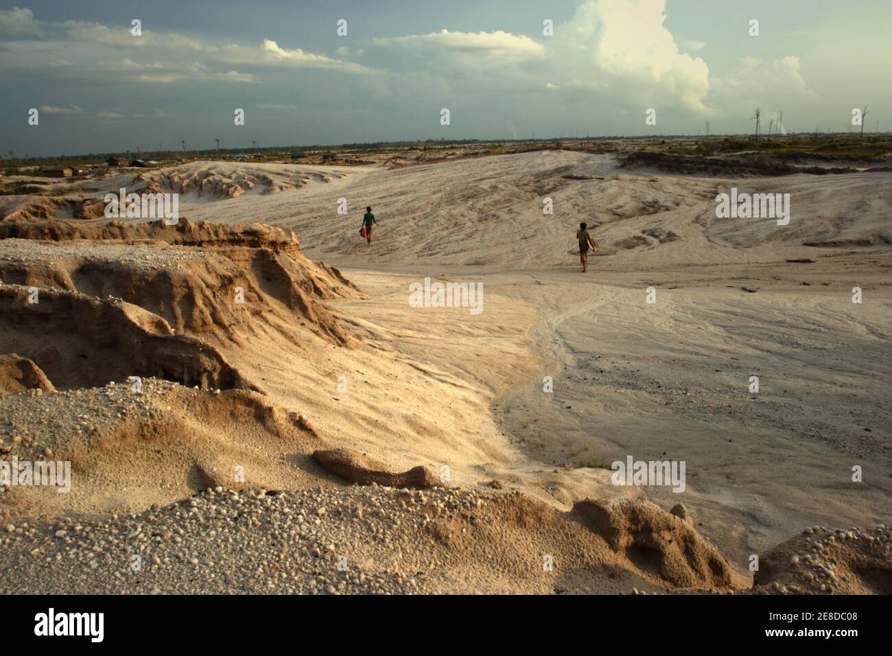 Gold miners walking down the sandy landscape of the small-scale gold ...