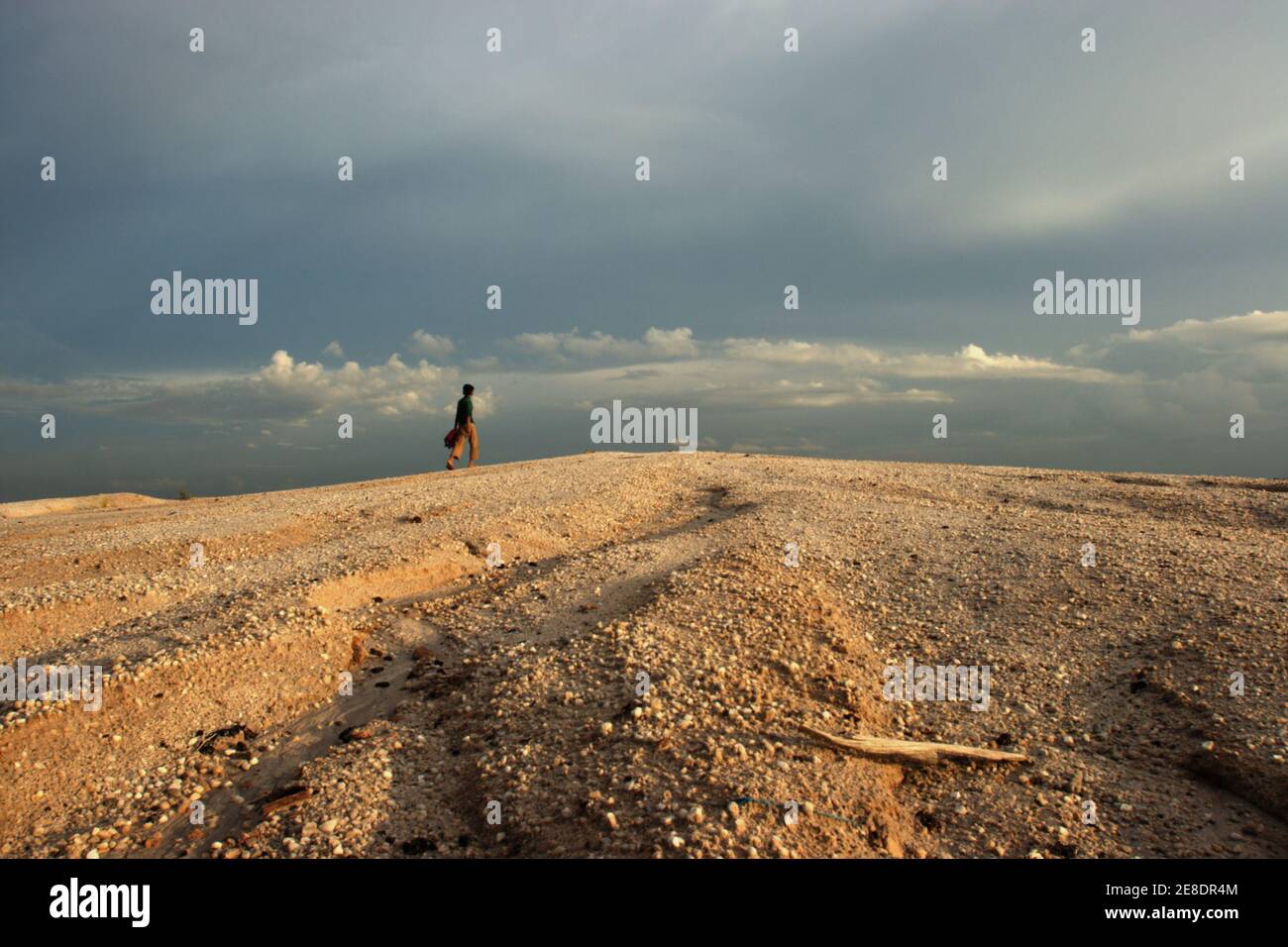 A gold miner walking on the sandy landscape of the small-scale gold ...