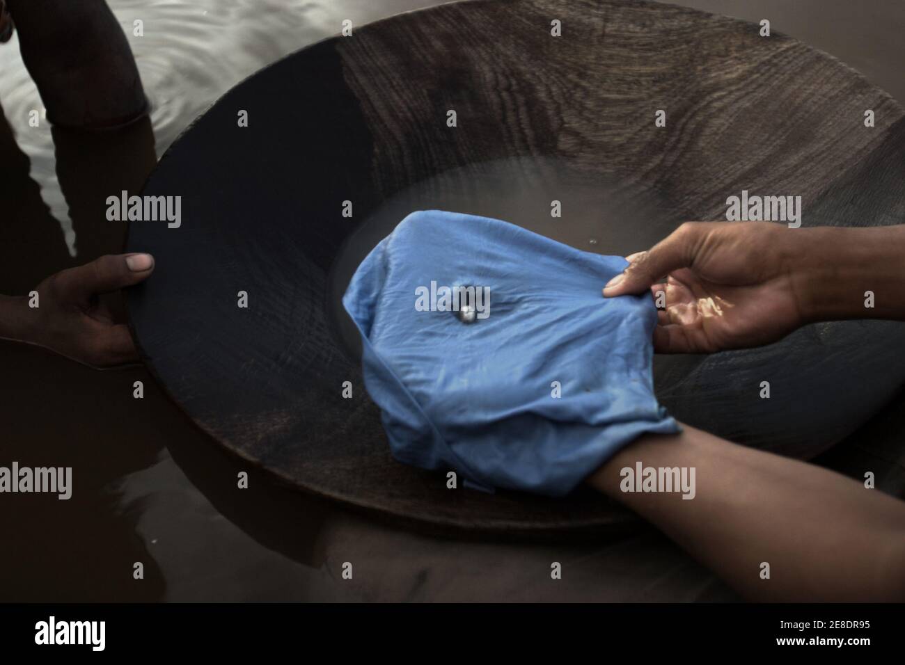 Gold miners processing gold particles with mercury amalgamation on a ...