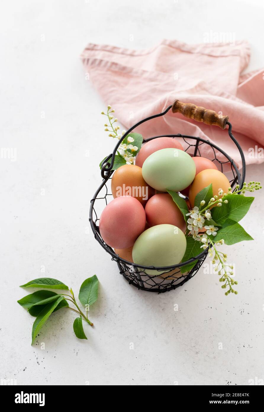 Assorted Easter eggs in basket with spring flowers and linen napkin ...